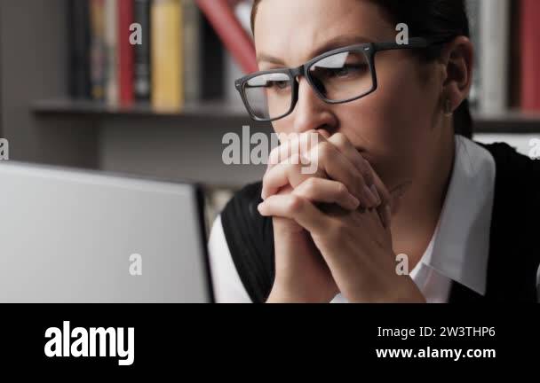 Upset woman looks at monitor screen. Pensive girl at workplace looks ...