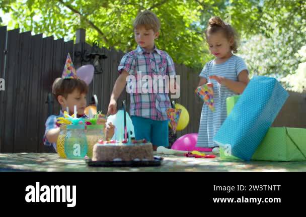 Two boys and one girl celebrating kids birthday party. Siblings trying ...