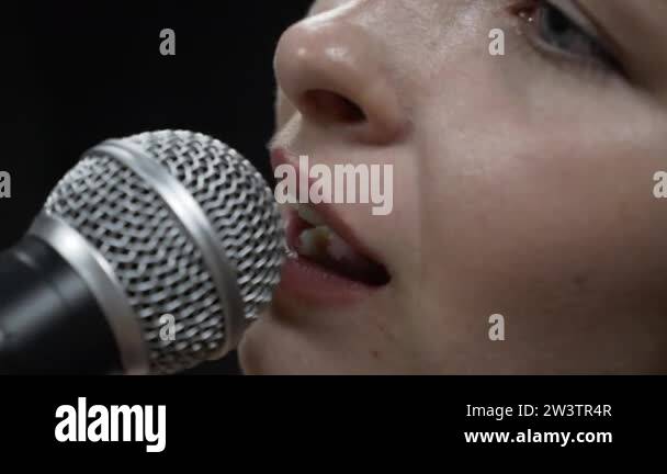 Woman face is singing song into microphone, extreme close up. Female ...