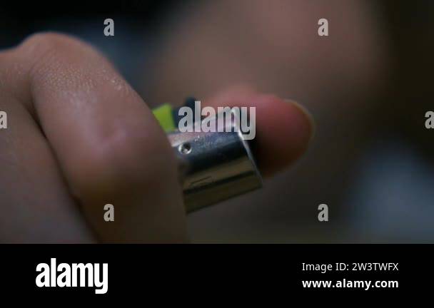 Close-up of a lighter igniting and setting fire to a cigarette. Girl ...
