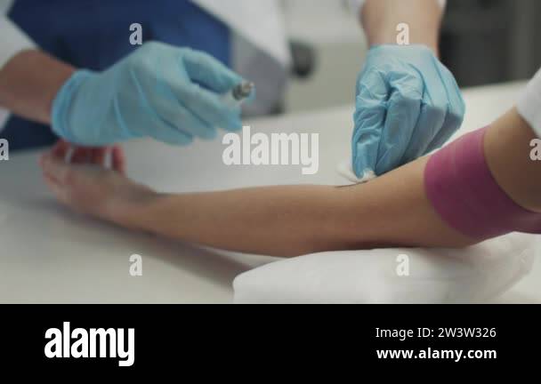 Close-up of an intravenous injection. The doctor jabs a syringe into a ...