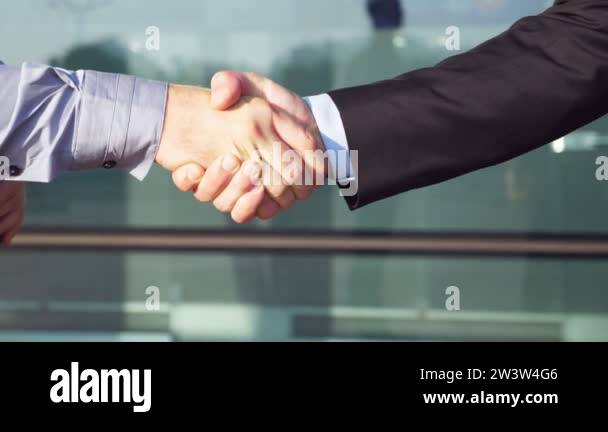 Two confident businessmen shaking hands after successful deal near ...