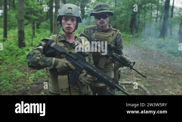 Squad of soldiers patrolling across the forest area, team with male and ...