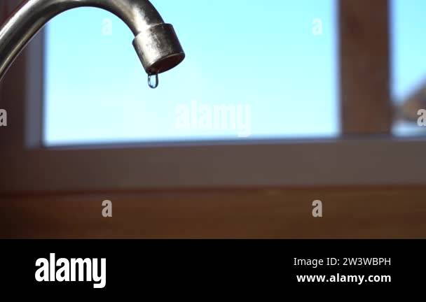 Dripping water from a faucet next to a window in the kitchen. Drops of ...