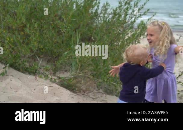 Adorable children fighting on dune sand. Brother and sister have fun at ...