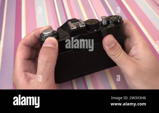 Close-up of male hands. Man is changing the shutter speed setting and ...