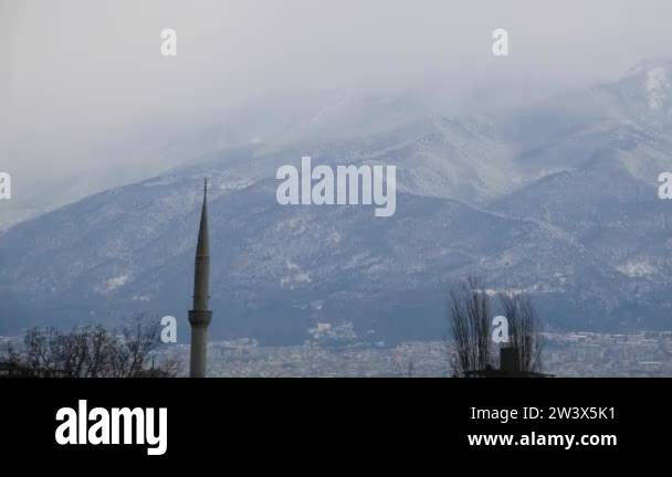 Dried trees, small mosque and minaret with background of Ulu mountain ...
