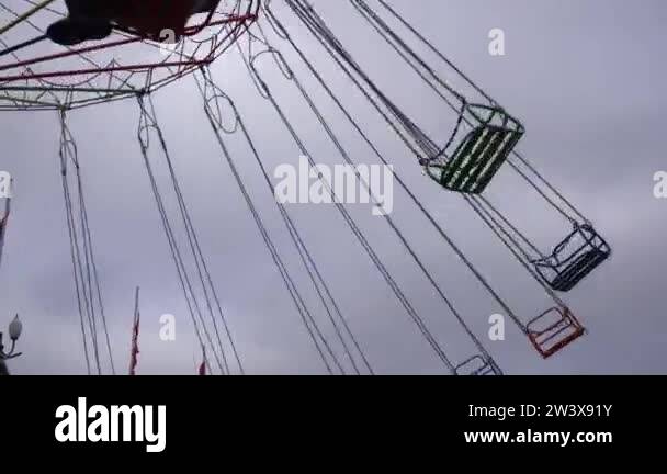 Two children ride a circular carousel on chains against the background ...