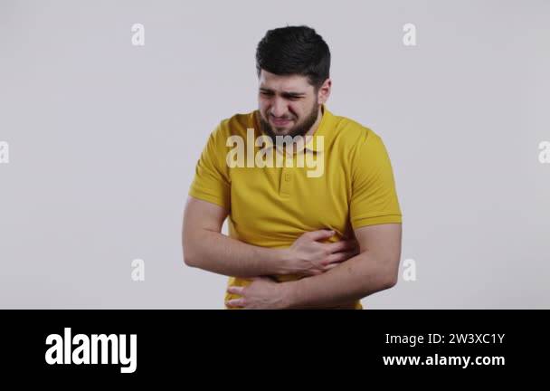 Man squeezing belly with hands because of abdominal pain. Guy suffering ...