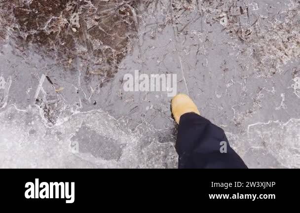 Female legs in white boots carefully walking on slippery road with ...