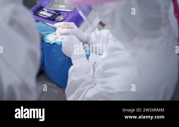 Dentist and nurse inside operating room working on oral case, patient ...