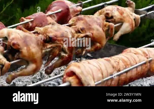 Rows of chickens, pork knuckle and muscles meat,cooking on a rotisserie ...