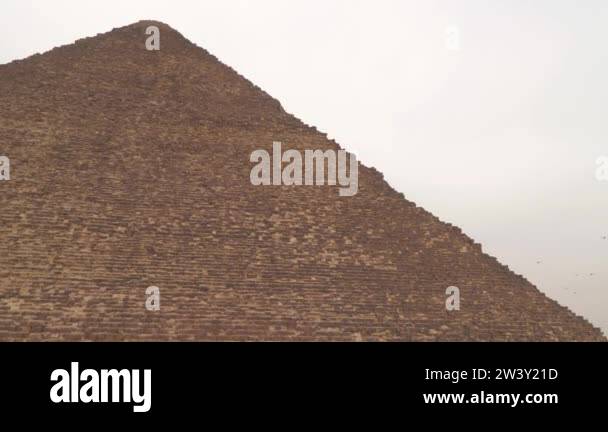 Pyramid of Cheops on the background of the cloudy sky. Birds fly in the ...