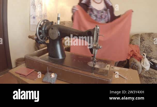 grandmother sews a red flag on an old sewing machine of the Soviet ...
