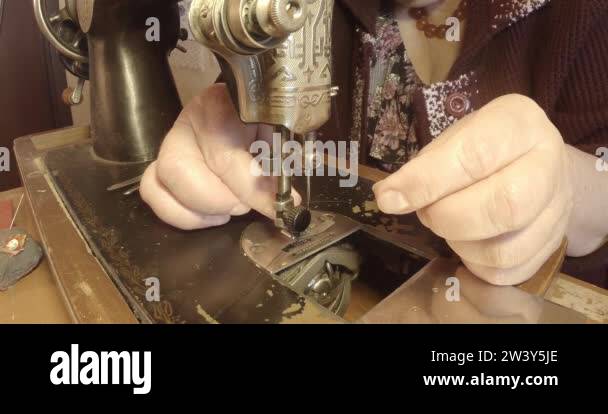 grandmother sews a red flag on an old sewing machine of the Soviet ...