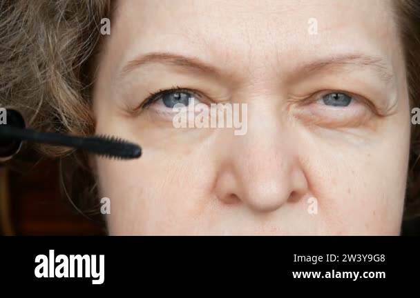 middle-aged woman does corrective eye makeup to correct the drooping ...