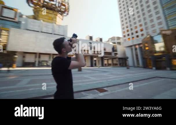 Young man photographs popular buildings in city. Action. Guy takes ...