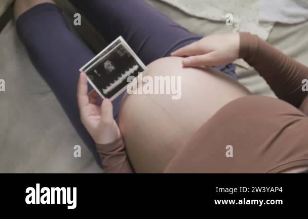 expecting pregnant woman with large belly looking at ultrasound scan at ...