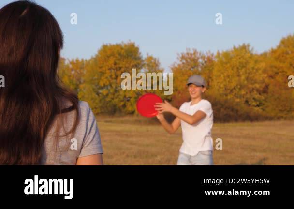 Girls throw a flying saucer to each other in the park. Young people ...