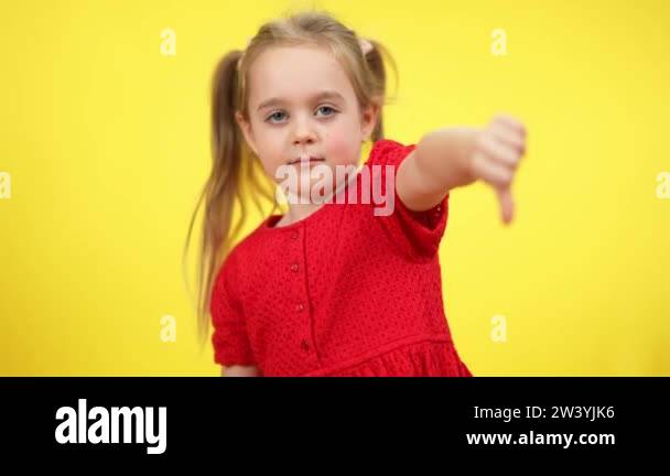 Charming little girl with pigtails showing thumb down shaking head no ...