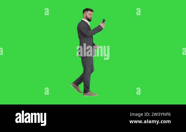 Handsome businessman walking and recording vlog on his phone on a Green ...