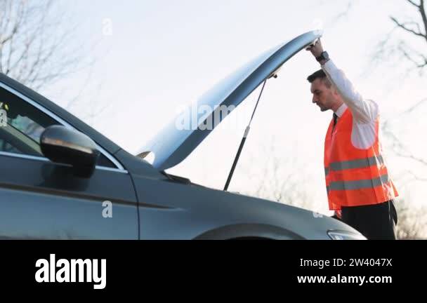Disappointed man in formal outfit opening bonnet of broke down car to ...