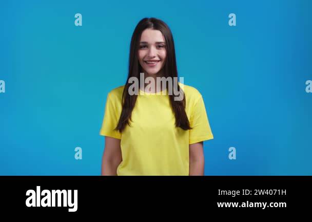 Pretty woman showing thumb up like sign over blue studio background. Positive young girl with ...