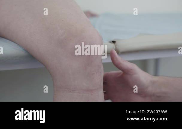 Doctor checking male knee joint in hospital. Close-up of Caucasian ...