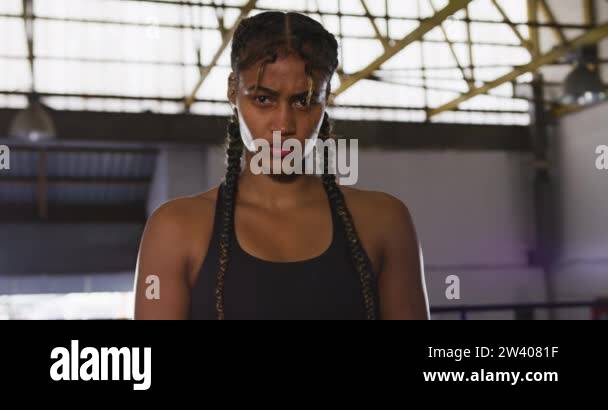 Portrait of mixed race female boxer with plaited hair wearing a vest ...