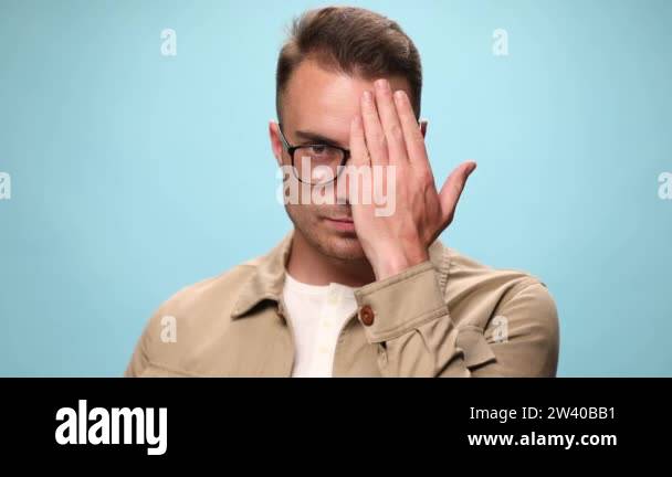 young casual man covering half of his face then revealing it and being ...