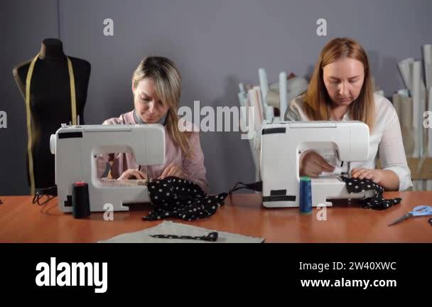 Two beautiful women sew with professional equipment in an atelier. They ...