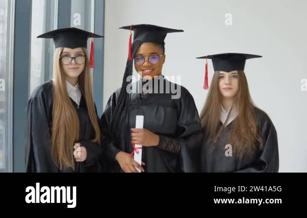 Three female students of different races with a diploma in hand. Higher ...