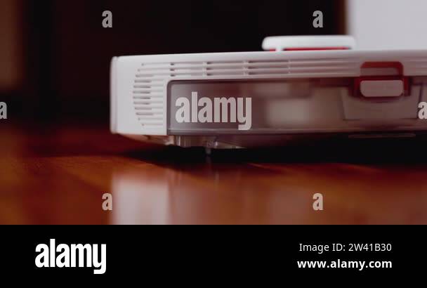 Smart Robot Vacuum Cleaner with lidar on wood floor. Robot vacuum cleaner performs automatic ...