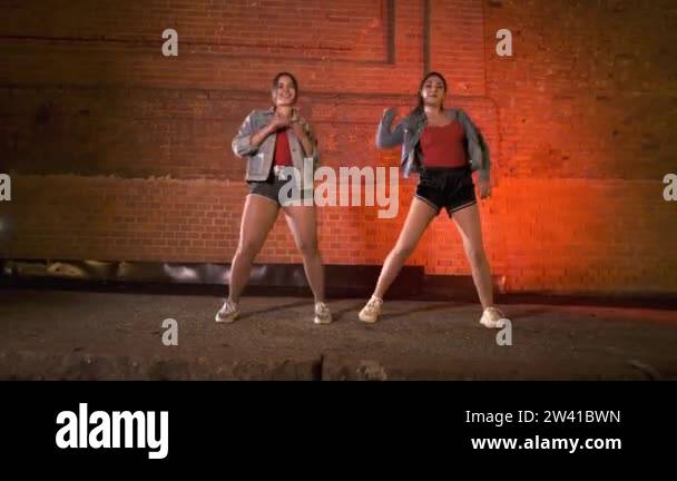 two happy girls dancing modern choreography, street dance against a ...