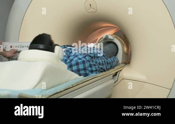 Woman doctor makes knee-joint MRI scanning. Young man patient on ...