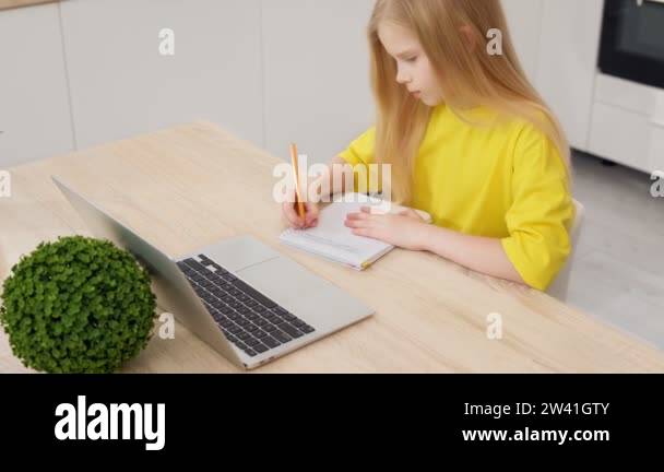 Blonde girl doing homework at home on a laptop. Online learning ...