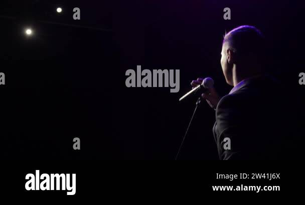 Man stand up comedian speaking jokes in micropphone stands on stage ...