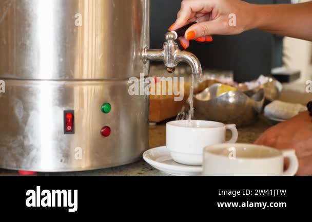 close-up, female hand turns on the tap of hot water container, then ...