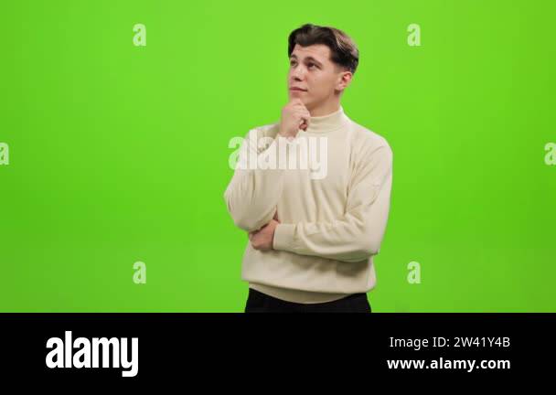 The man is standing and thinking. He is holding his hand to his face ...