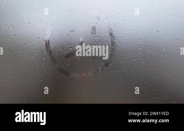 drawing of a sad face on the fogged glass. a symbol of happy mood and ...