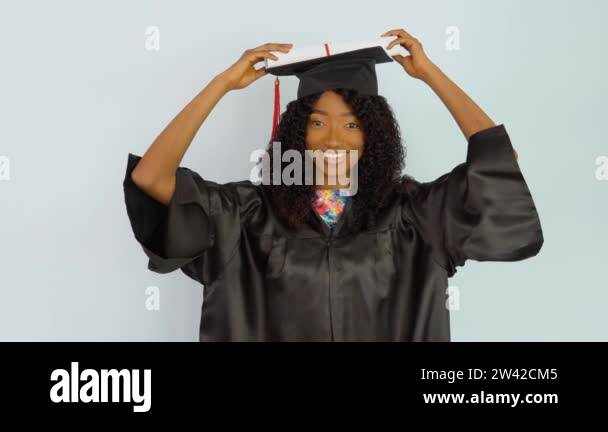 A young African American woman in a black gown and a masters hat stands ...