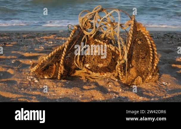 Old used dirty fishing nets with rusty wire, garbage dumped on the sea ...
