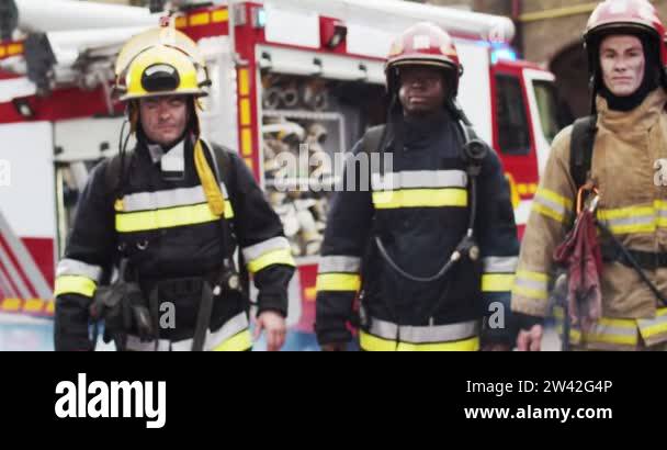 Medium plan of three firefighters approaches from fire van with ...