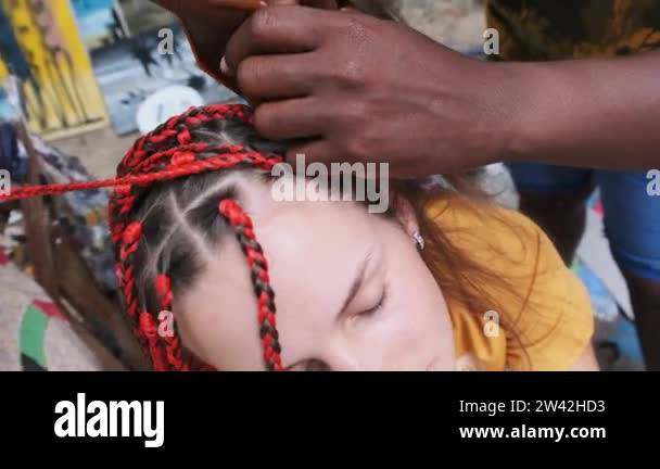 African Woman Weaving African Braids with Red Kanekalon Outdoor ...