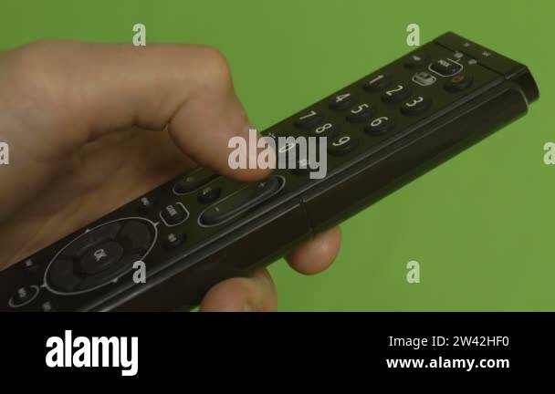 Male hand changing channels with remote control on a green screen. Side ...