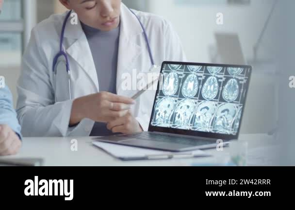 Tilt up shot of young mixed raced female doctor zooming and pointing at ...