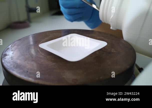 Lab technician using an scale to weight powdered test sample ...