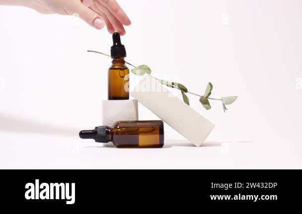 Hand is opening brown dropper glass bottle and pouring out serum of ...