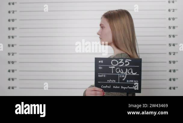 Side profile mugshot of female person holding sign while being ...