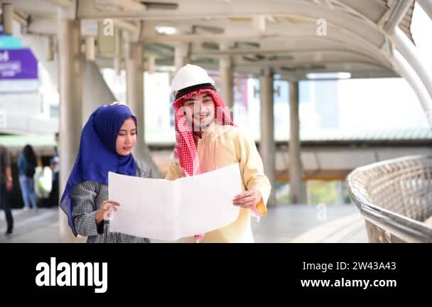 Arab engineer consult construction project together hold blueprint, pointing at under ...